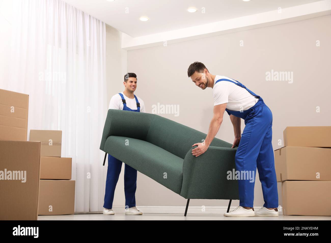 Professional movers carrying sofa in new house Stock Photo - Alamy