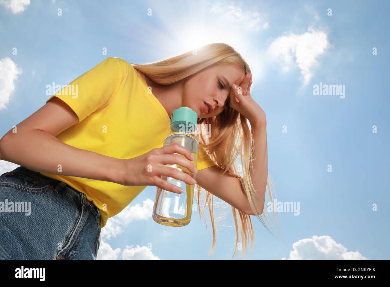 Woman with bottle of water suffering from heat stroke outdoors Stock ...