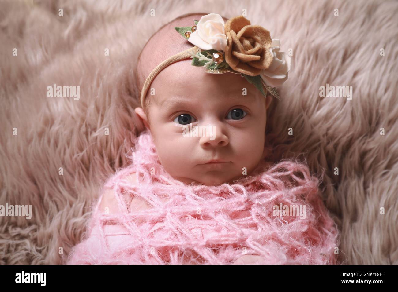 Cute newborn baby girl with floral headband lying on fuzzy rug, top ...