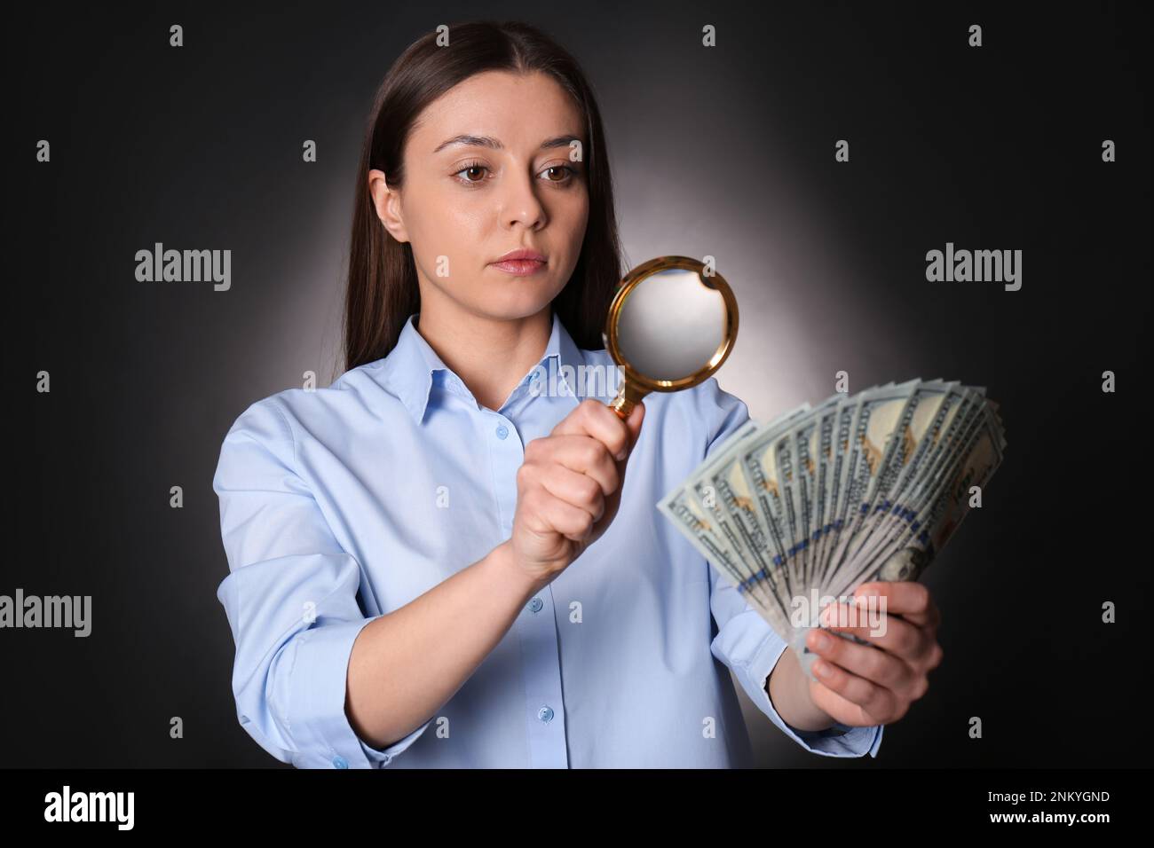 Expert authenticating 100 dollar banknotes with magnifying glass ...