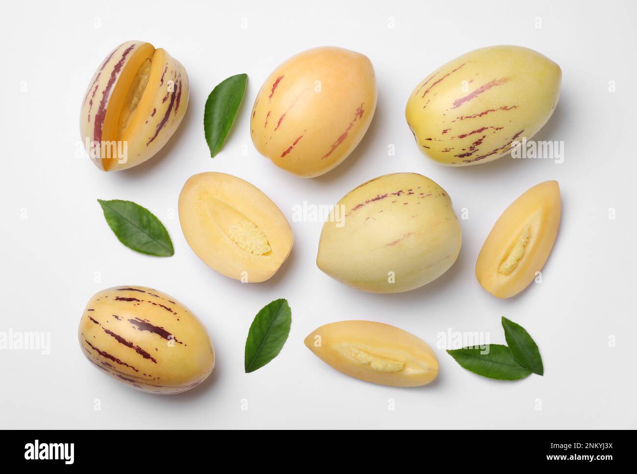 Whole and cut pepino melons with green leaves on white background, flat ...