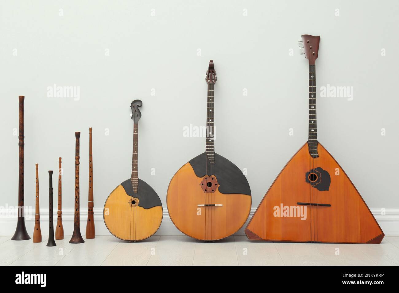 Set of different wooden musical instruments near white wall indoors ...