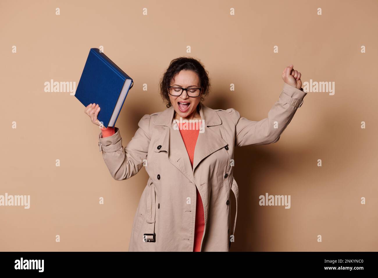 Beautiful happy female professor has fun, dances with hardcover book in ...