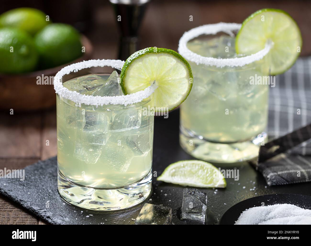 Margarita cocktail with ice, lime slice and salt rim on a black slate ...