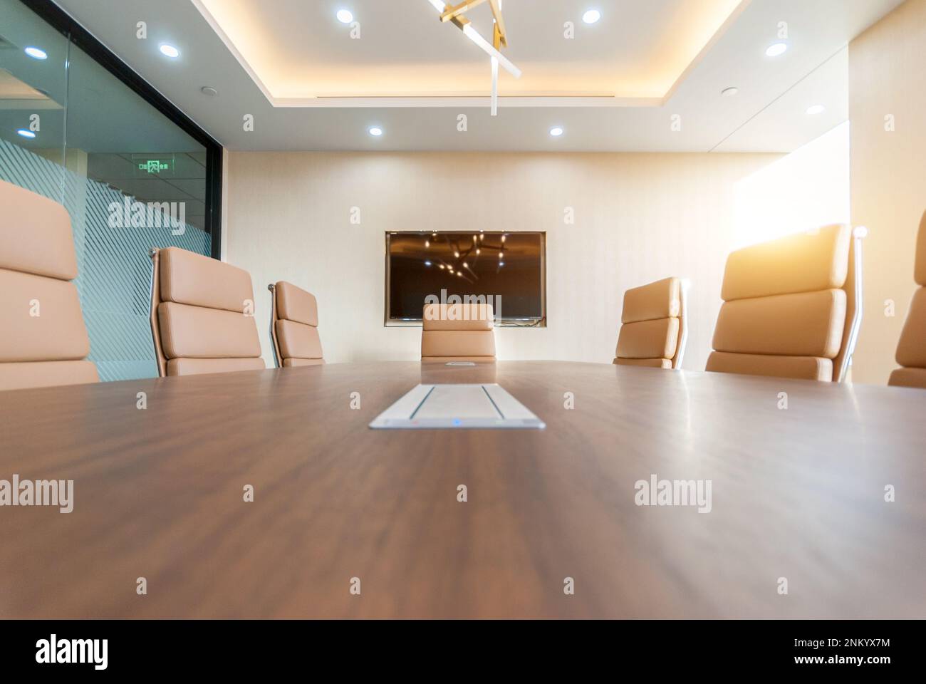 A modern conference room with a large wooden table and numerous chairs ...