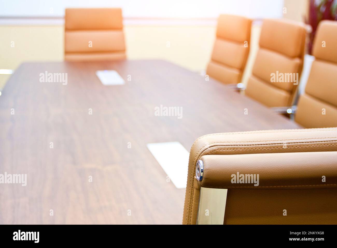 A modern conference room with a large wooden table and numerous chairs ...