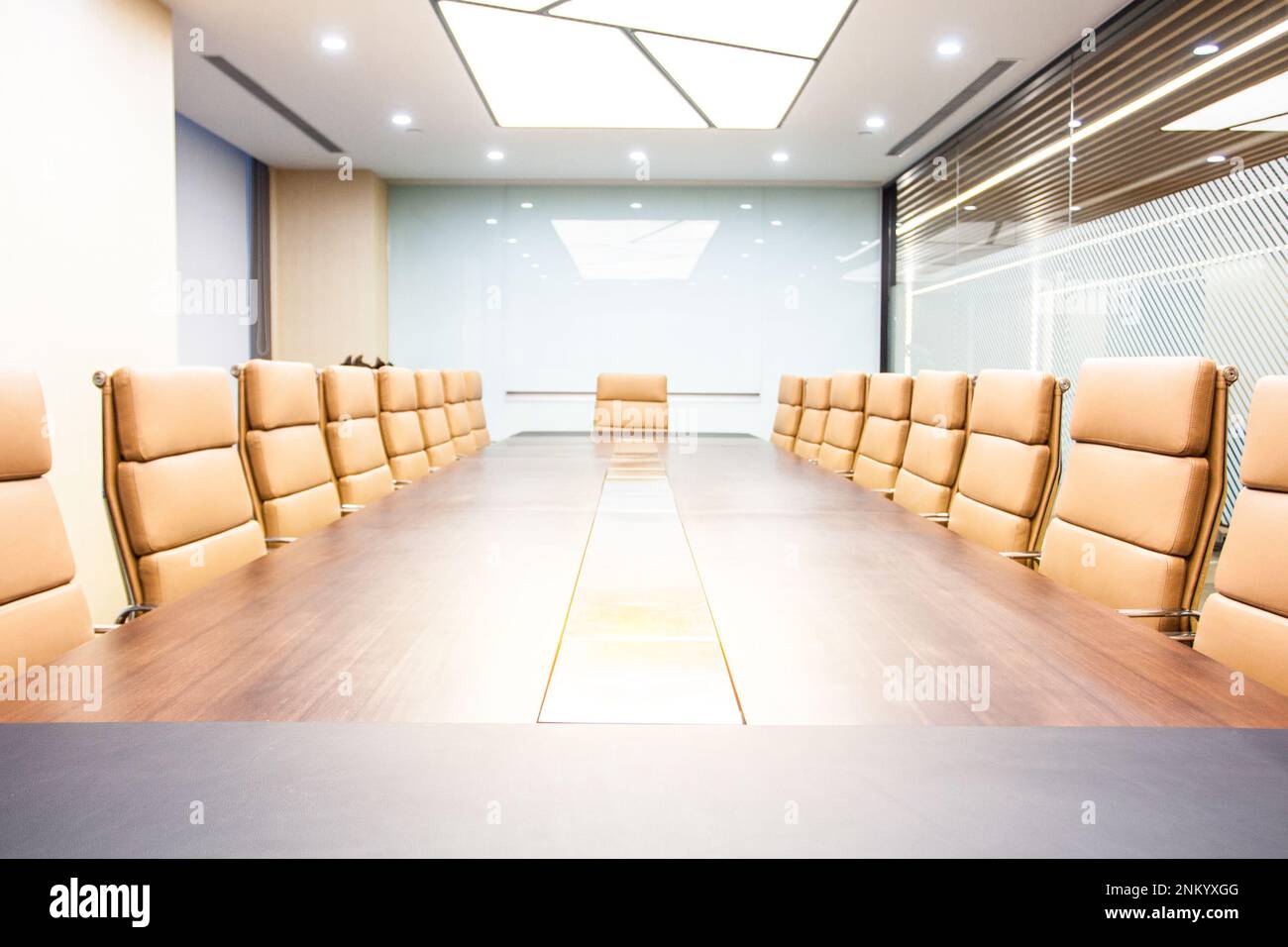 A modern conference room with a large wooden table and numerous chairs ...
