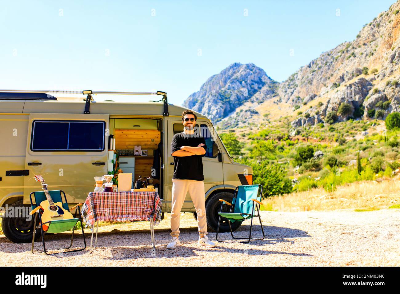 young man relaxing in rv, camping in a trailer mountain background ...