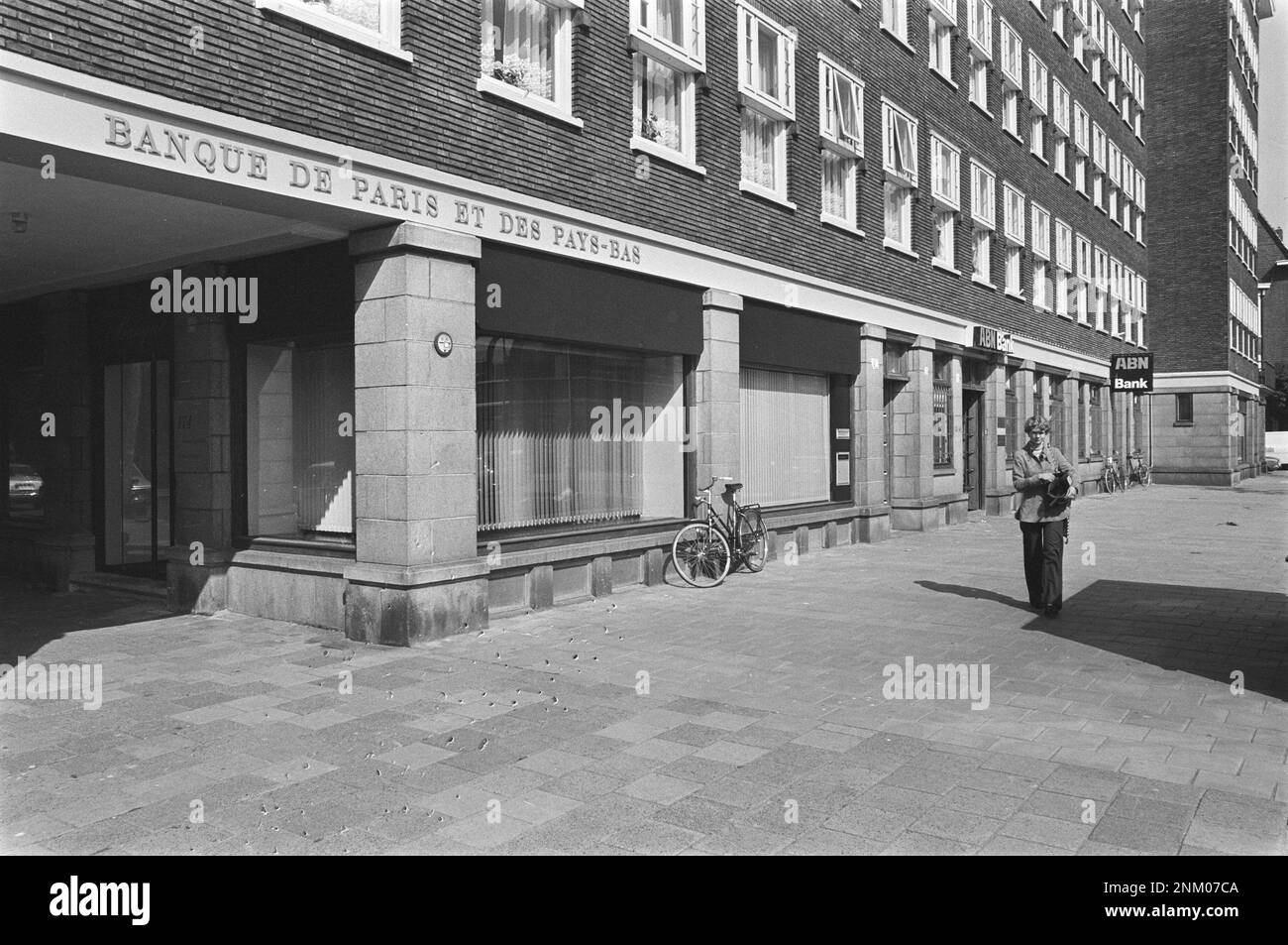 Woman walking on sidewalk along the exterior of the Banque de Paris et ...