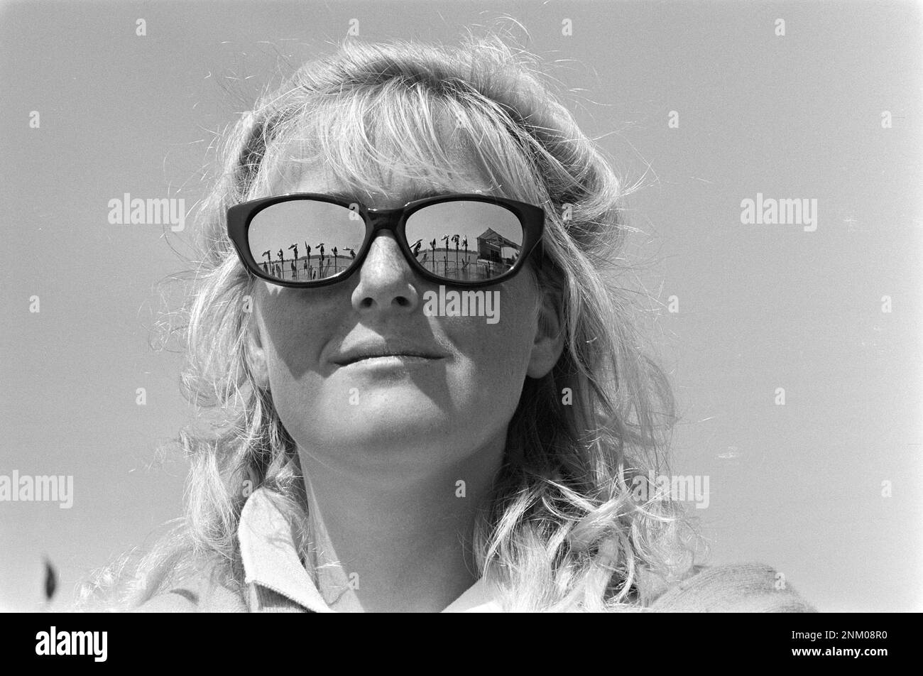 Woman wearing mirrored sunglasses watching a pole sitting competition ...