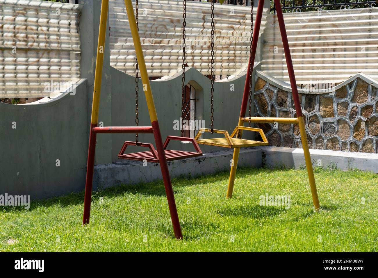 Old and rusty children's swing. Painted with red and yellow colour ...