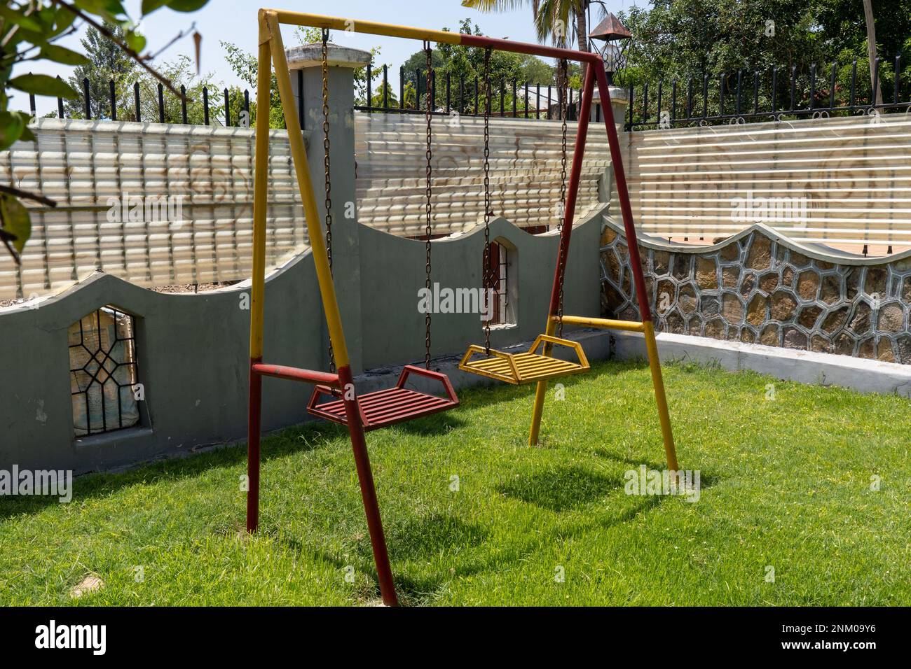 Old and rusty children's swing. Painted with red and yellow colour ...