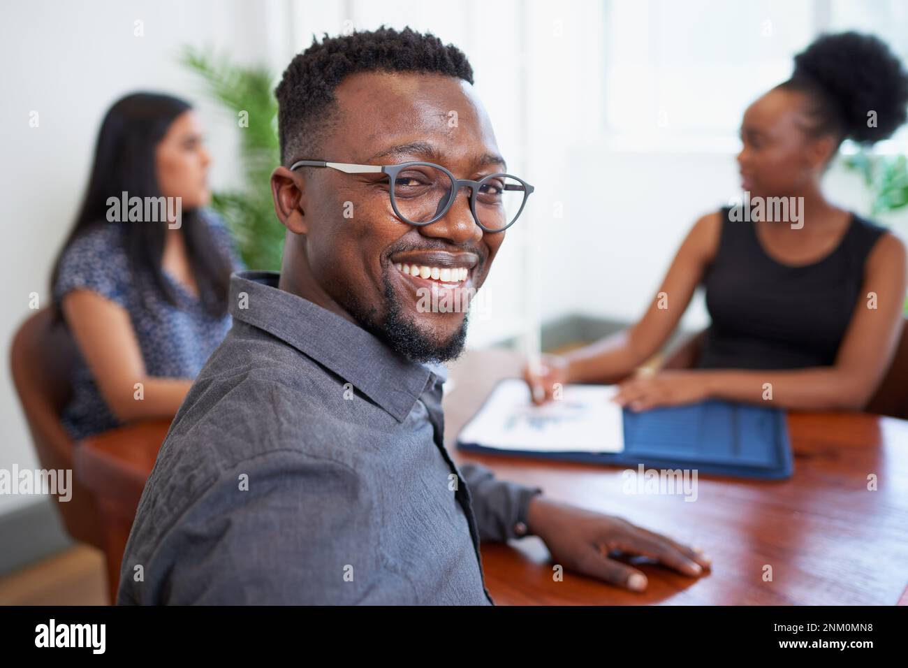 Black businessman turns to camera at conference table with female ...