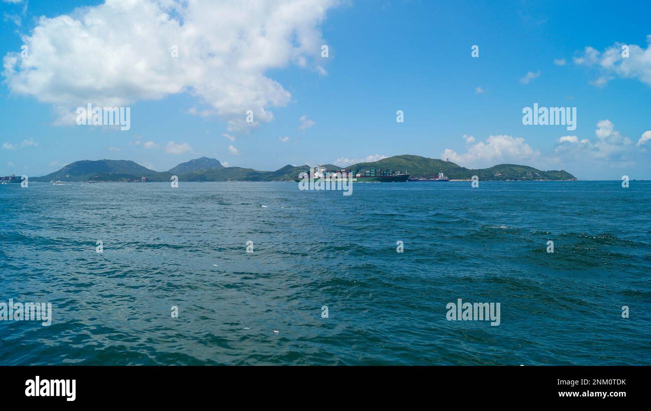 Horizontal view of sea with a container ship with mountains under the ...