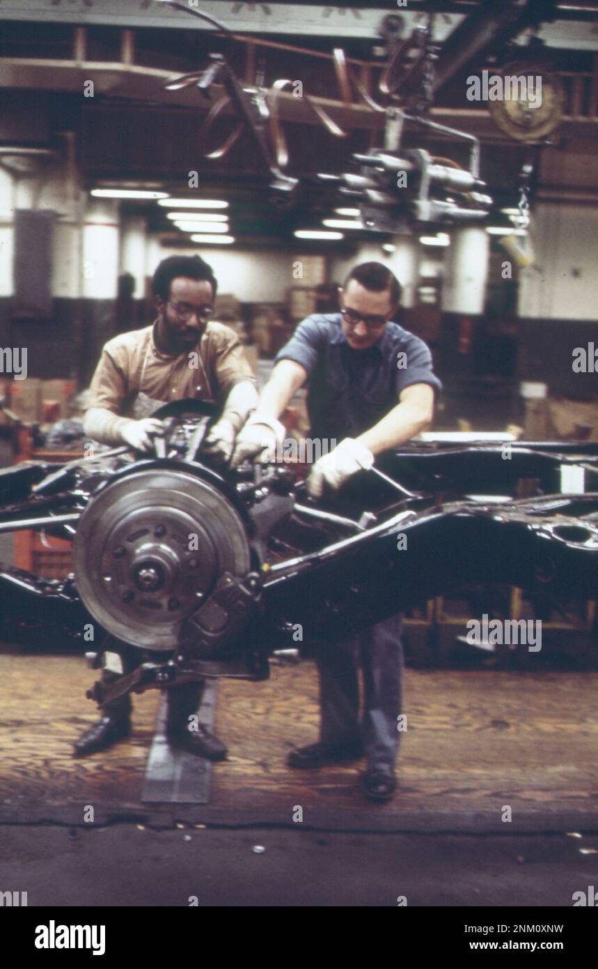 1970s America: On the Cadillac assembly line--attaching axle to frame ...