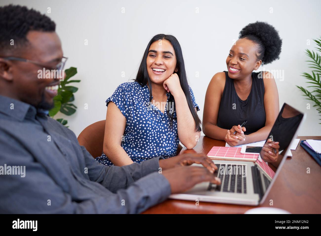Three diverse colleagues laugh and joke in the workplace, friendly ...