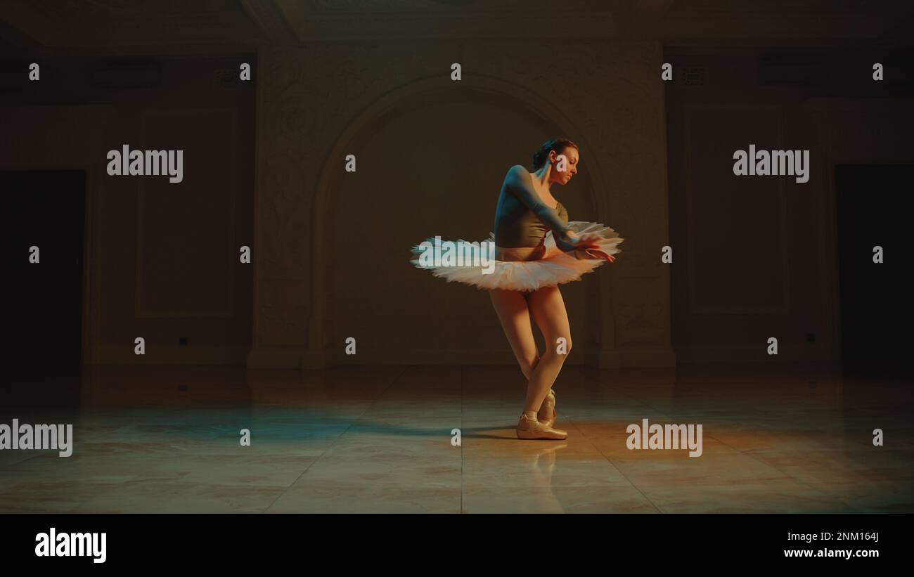 Cinematic shot of beautiful classical ballet female dancer in white tutu dress dancing in ...