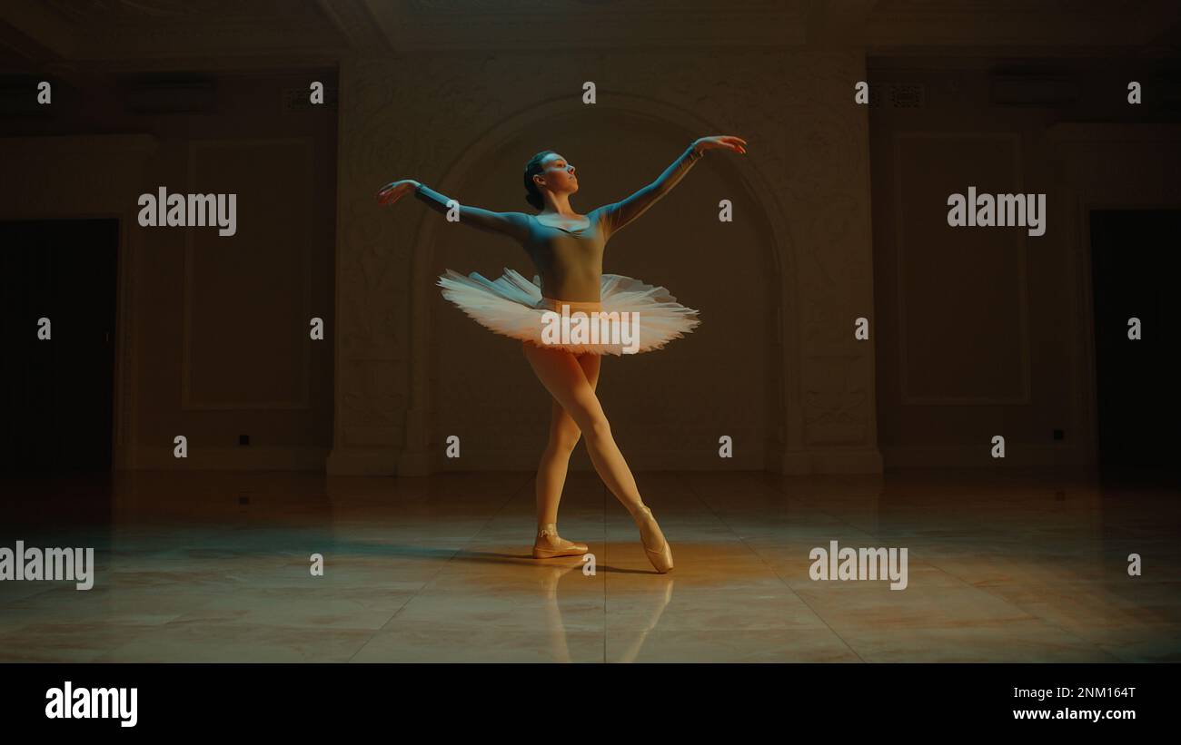Cinematic shot of beautiful classical ballet female dancer in white tutu dress dancing in ...