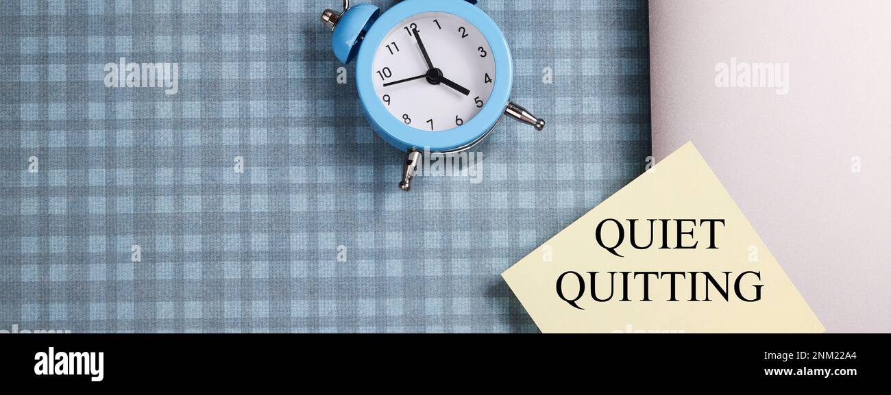 quote 'Quiet quitting' on yellow sticker on computer with clock and ...