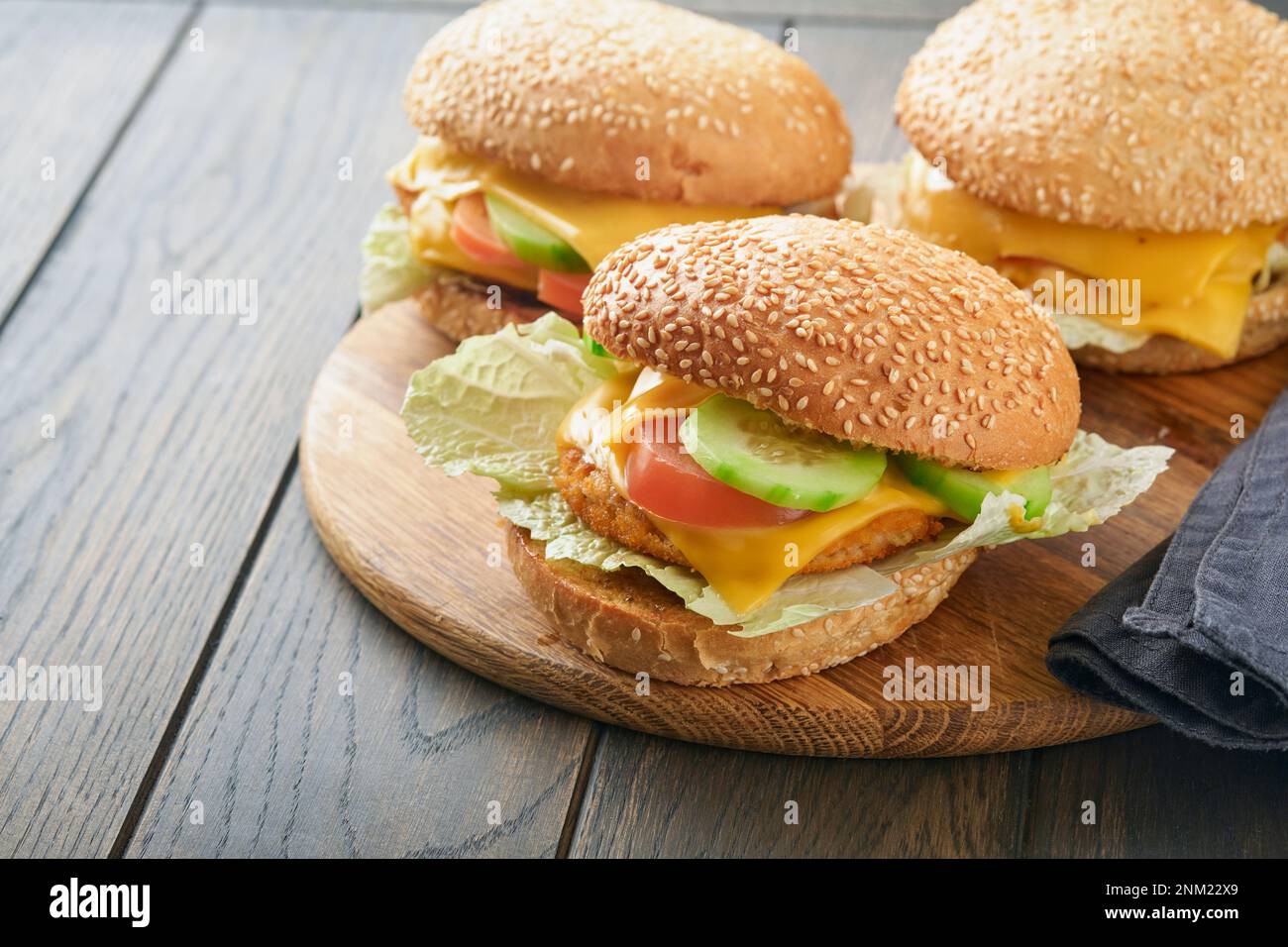 Homemade fish burger with vegetables on rustic wooden board. Side view ...
