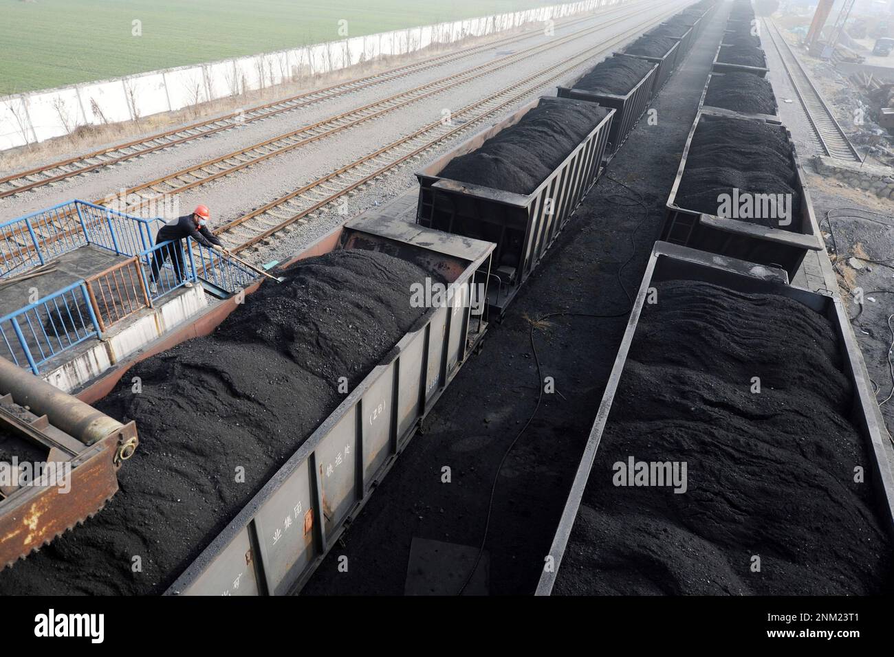 A worker shovels up coal on a freight train for quality inspection at a state-run coal mine in ...