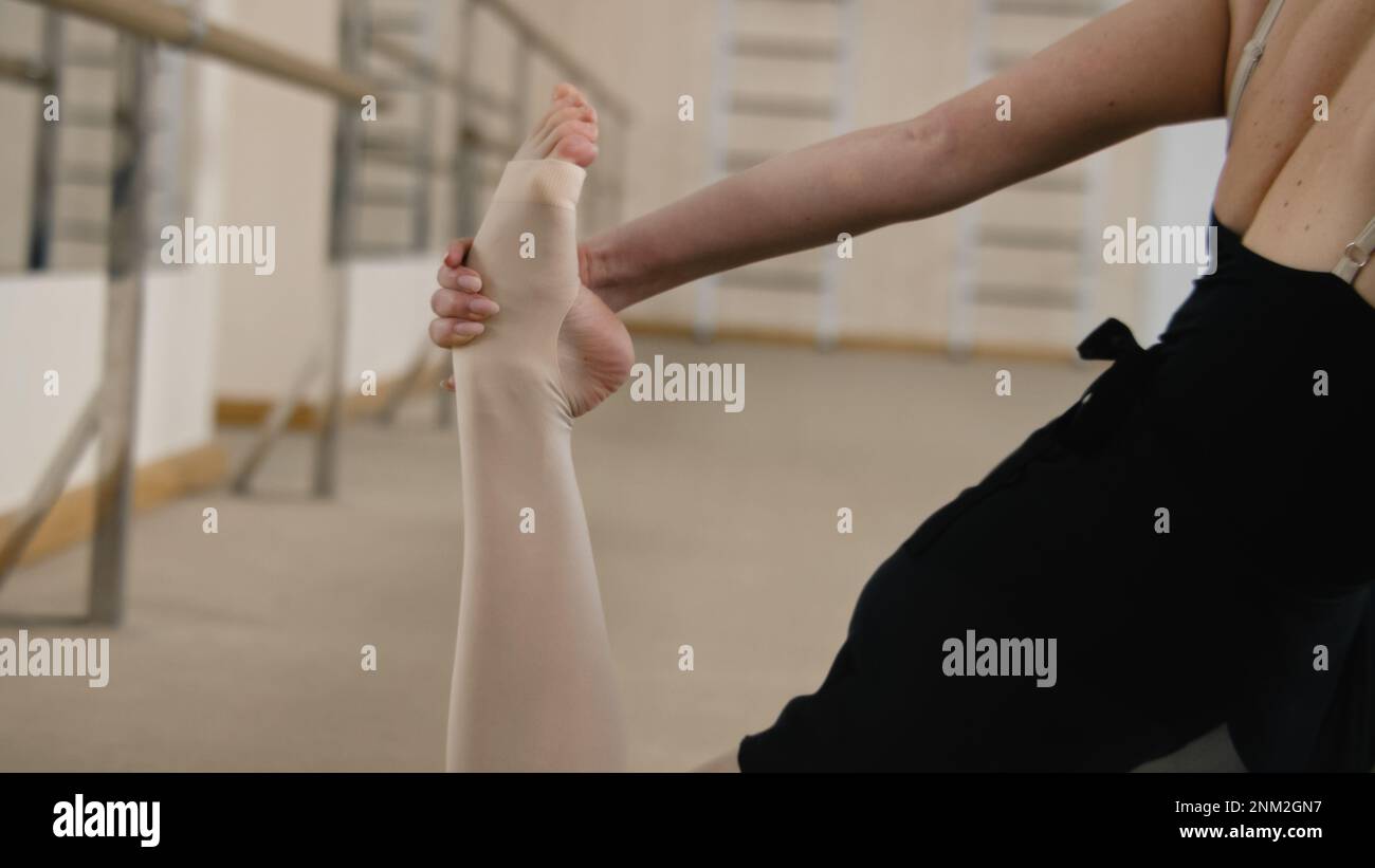 Ballerina in training bodysuit stands near ballet barre in dance studio ...
