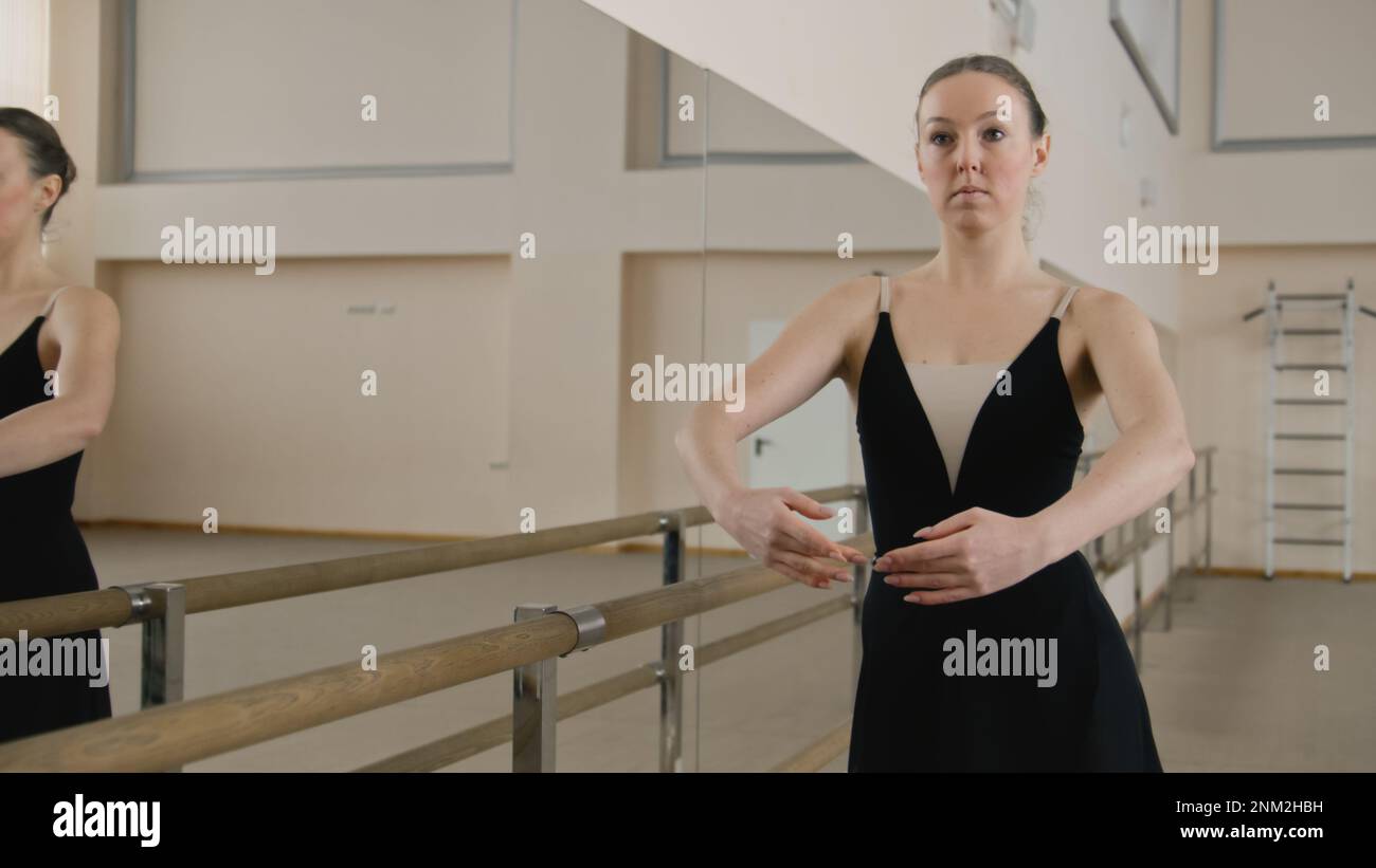Graceful adult ballerina in training bodysuit rehearses near ballet ...