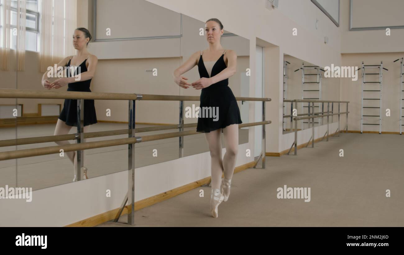 Ballerina in training bodysuit stands on tiptoe in front of ballet ...