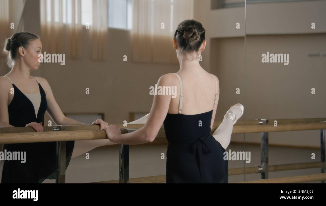 Female ballet dancer doing gymnastic exercises in front of the mirror ...