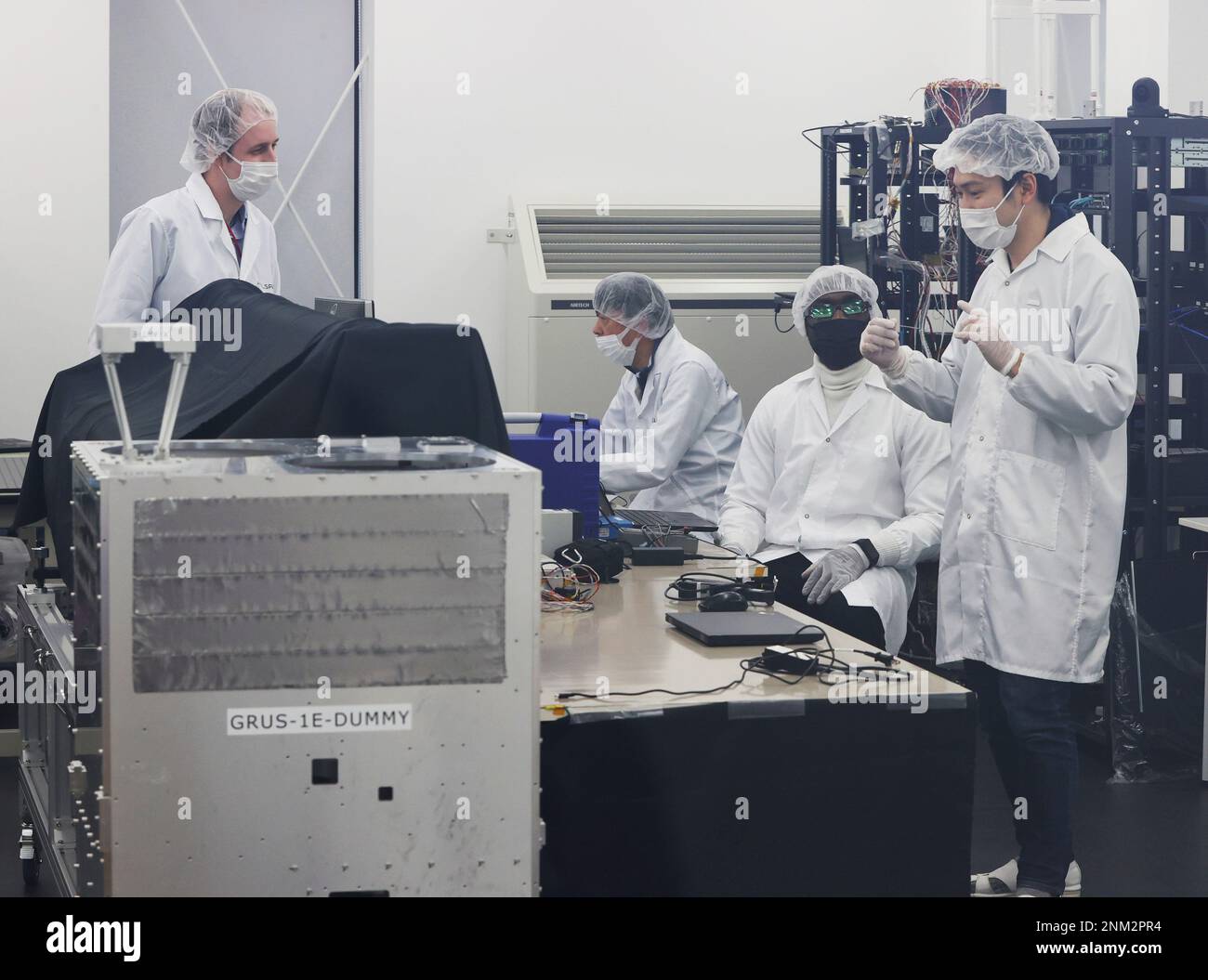 Engineers assemble a small satellite in a clean room in Chuo Ward ...