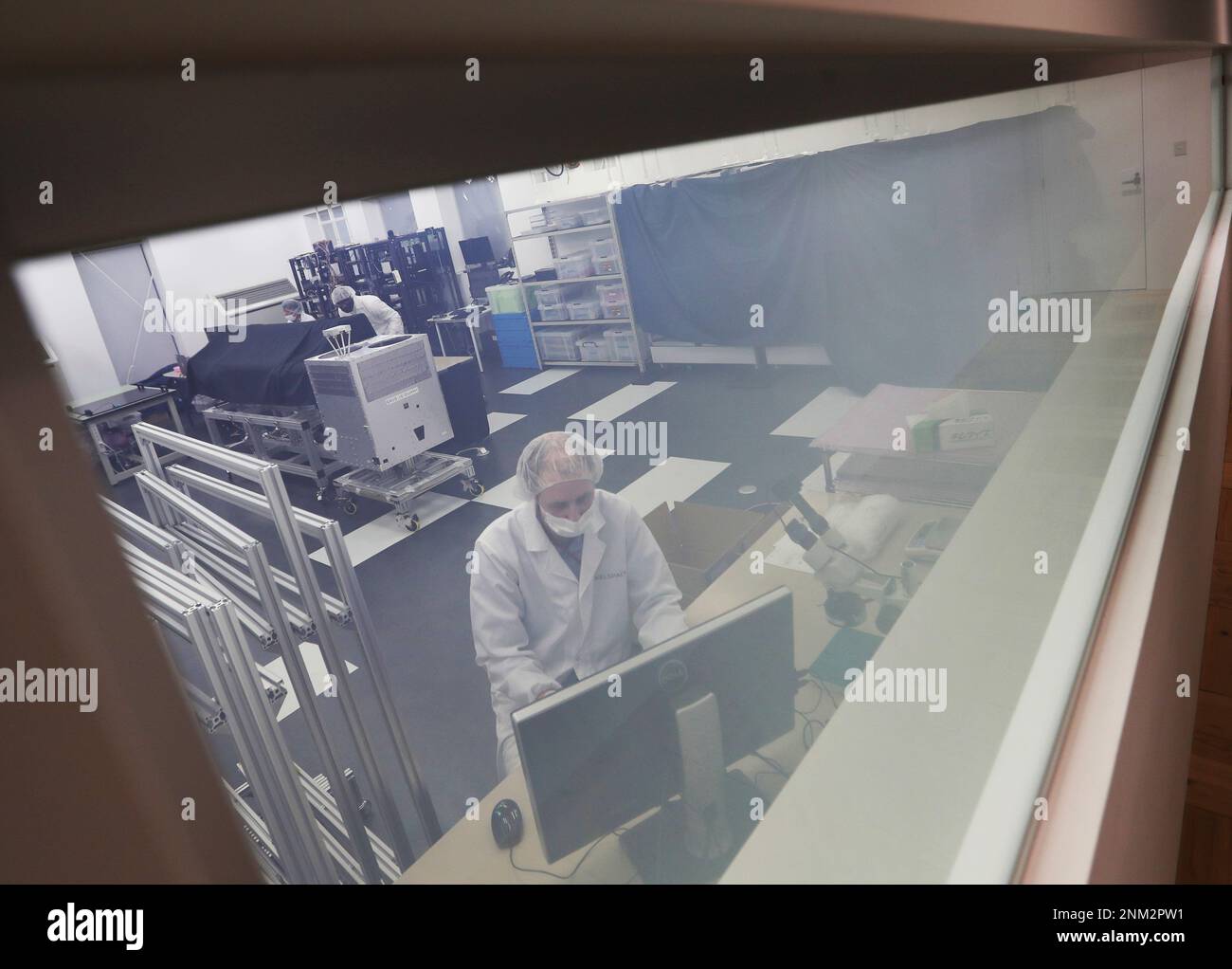 Engineers assemble a small satellite in a clean room in Chuo Ward ...