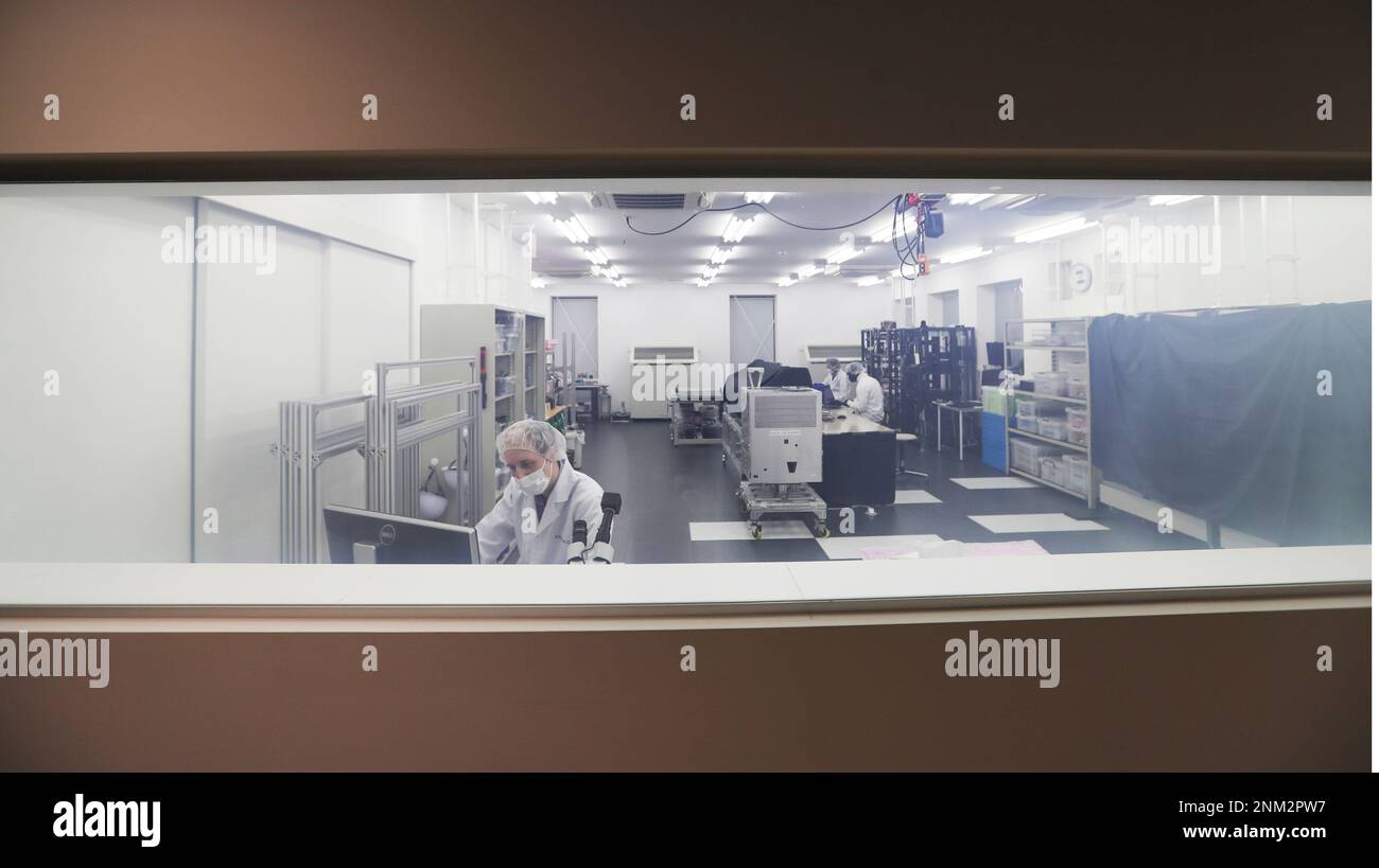 Engineers assemble a small satellite in a clean room in Chuo Ward ...