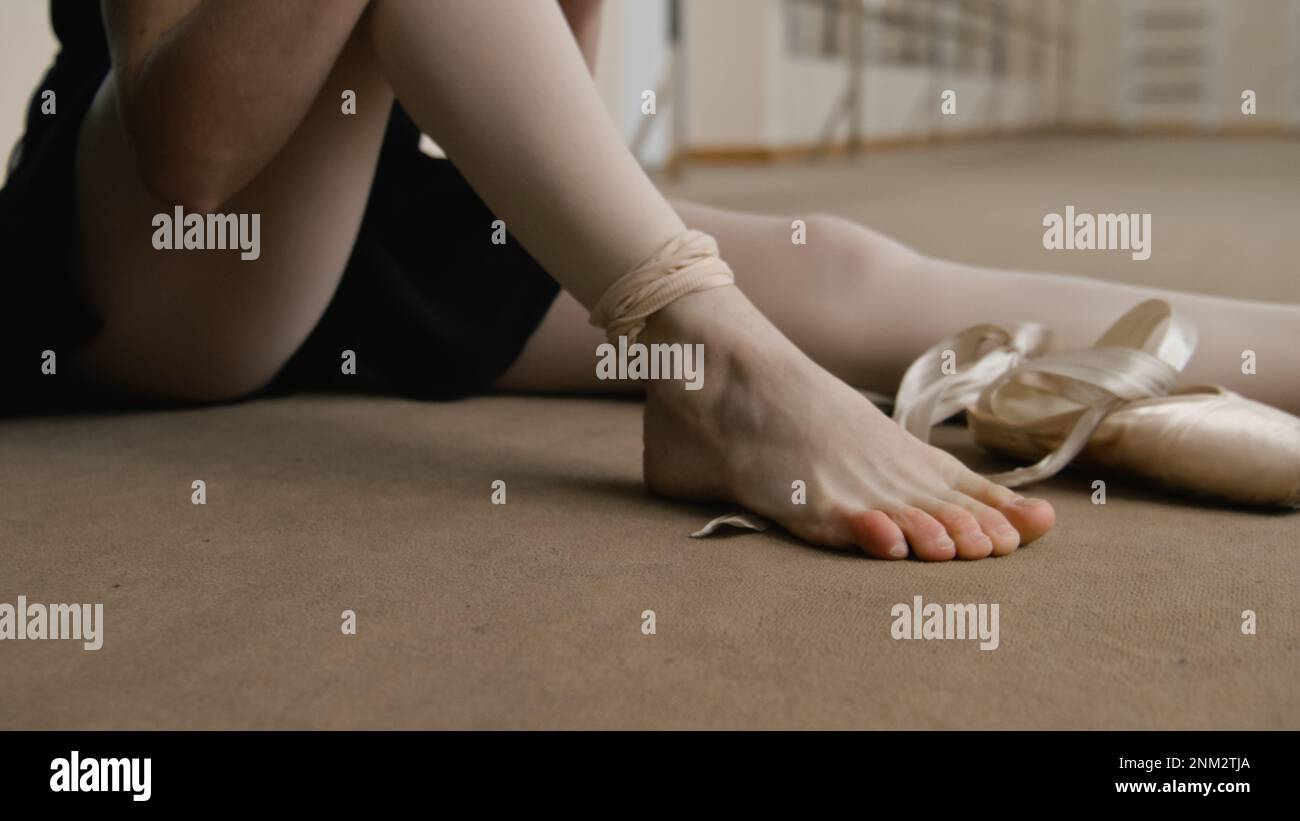 Close up shot of female ballet dancer taking off her pointe shoes after ...