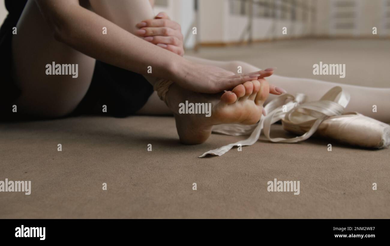 Close up shot of female ballet dancer taking off her pointe shoes after ...