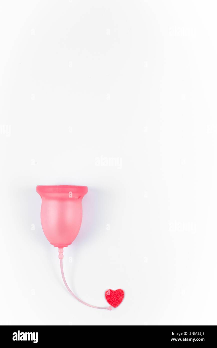 Pink menstrual cup with red hearts on white background. Alternative ...