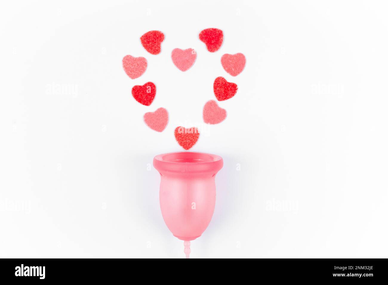 Pink menstrual cup with red hearts on white background. Alternative ...