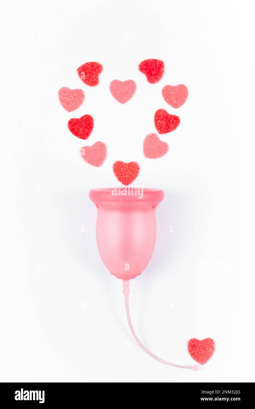 Pink menstrual cup with red hearts on white background. Alternative ...