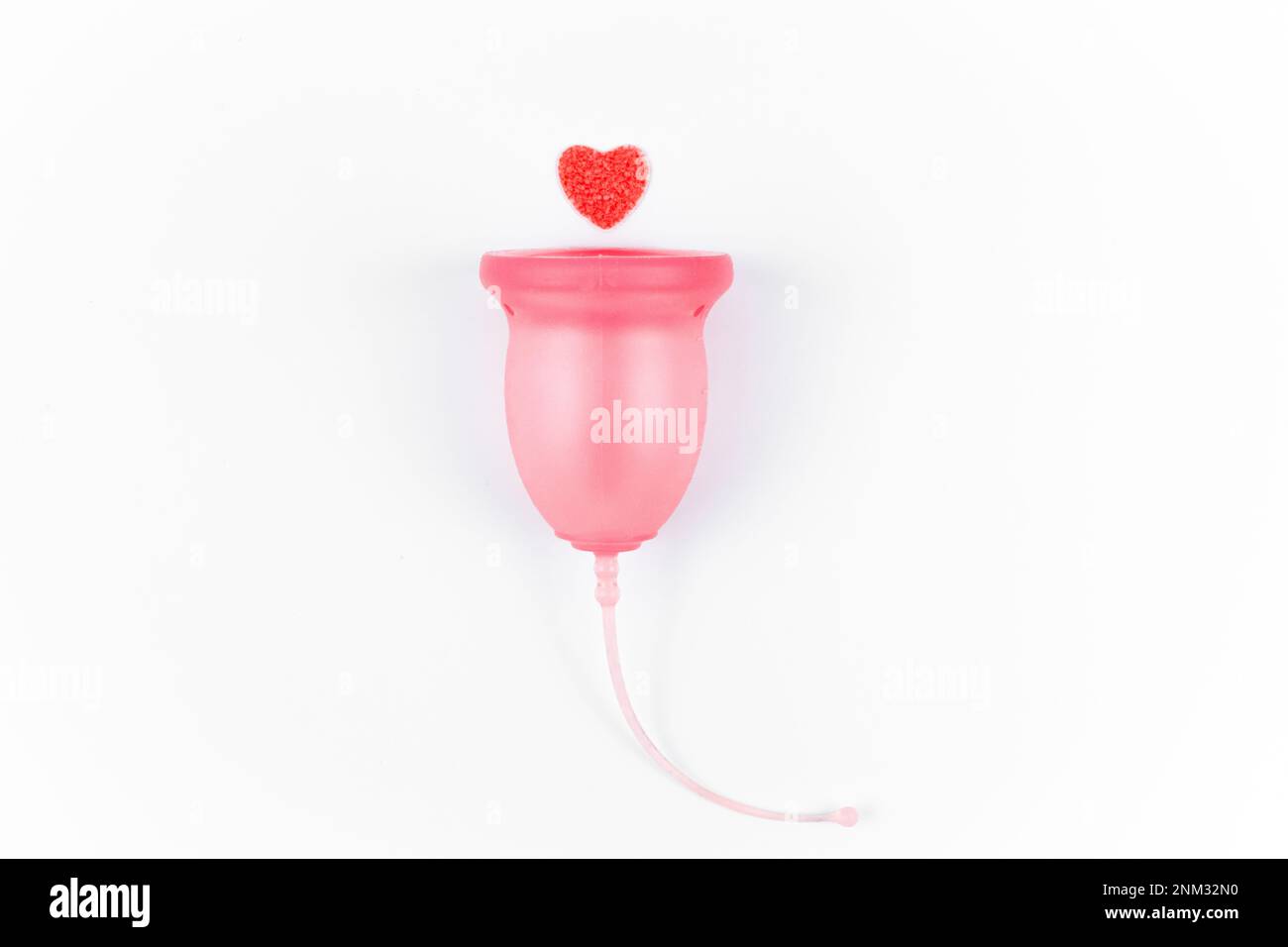 Pink menstrual cup with red hearts on white background. Alternative ...