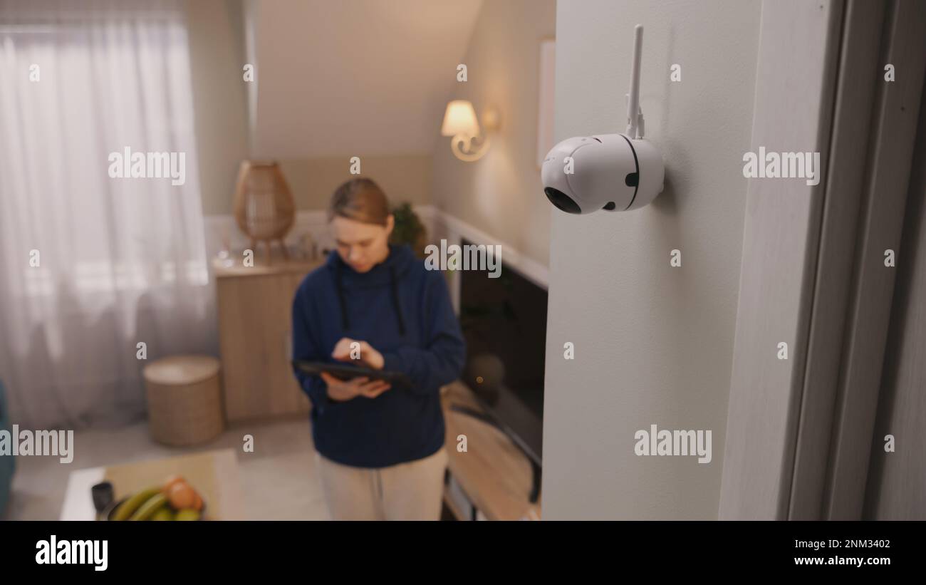 Caucasian woman installs security camera. Woman sets up angle of CCTV ...