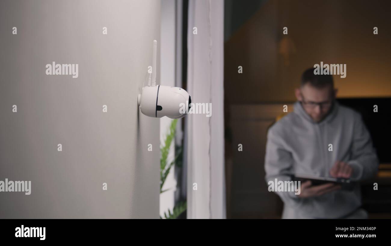 Man sets up security camera at home for the night. He turns on night ...