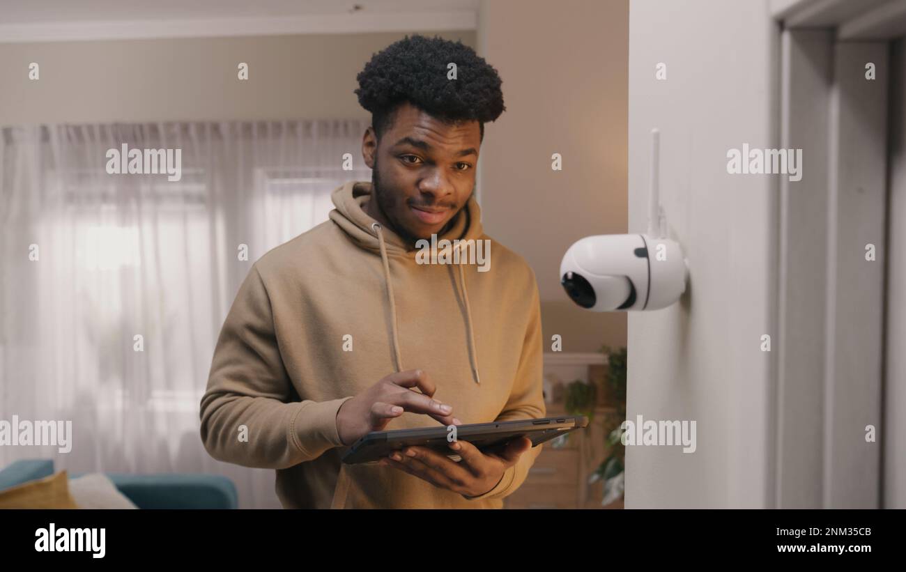 African American man installs security camera. Man sets up angle of ...