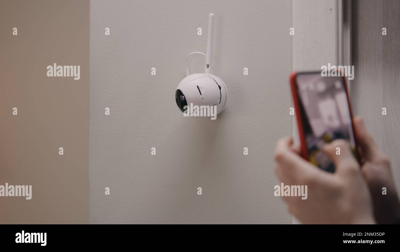 Caucasian woman completes installation of security camera. Woman sets ...