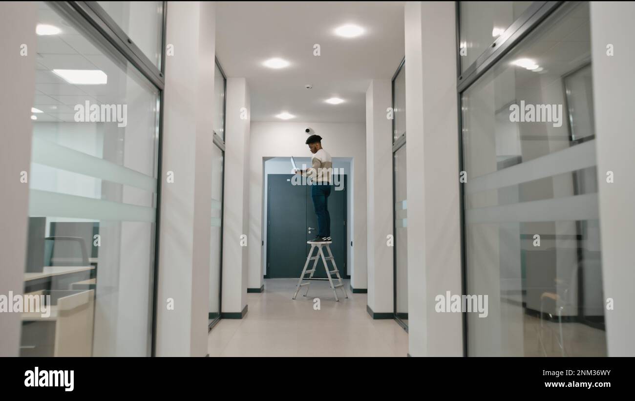 African american installer sets up security cameras in office room ...