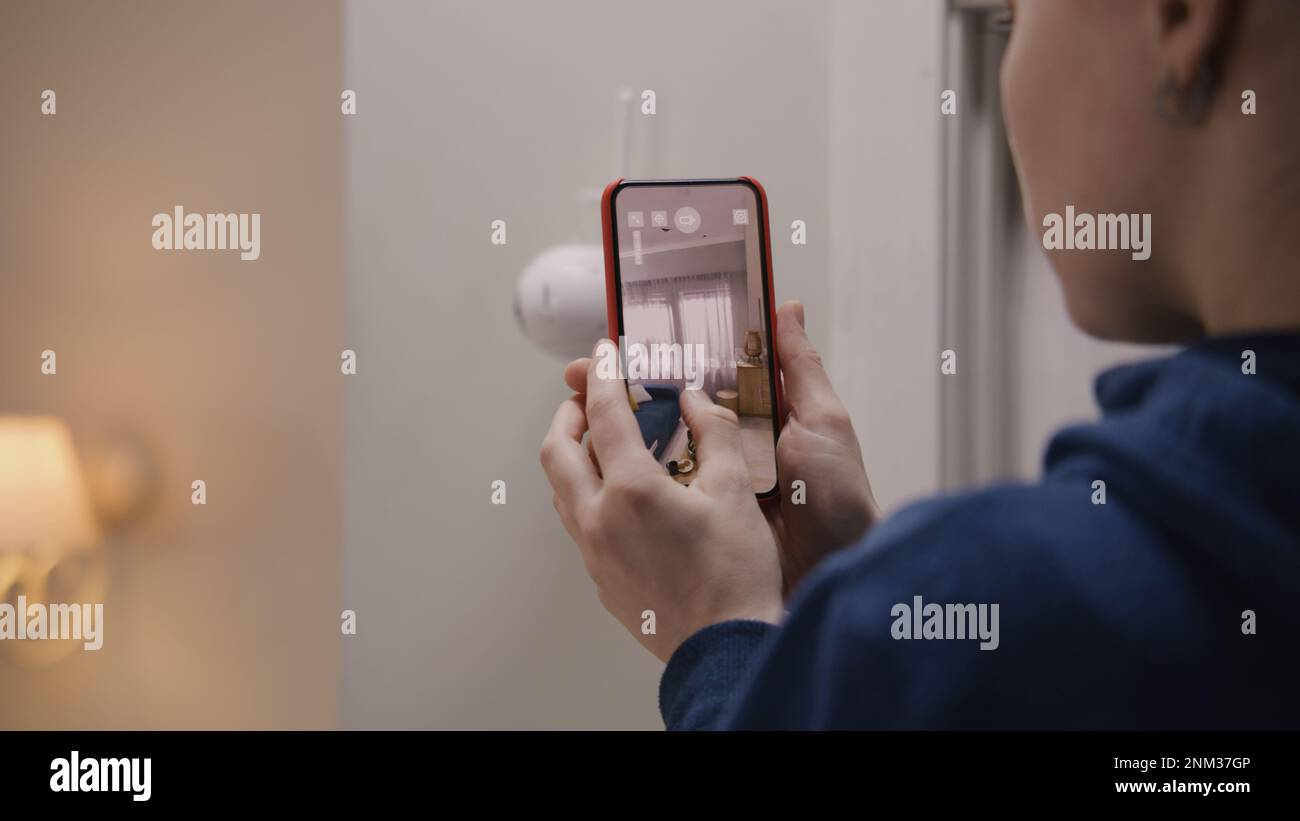 Caucasian woman completes installation of security camera. Woman sets ...