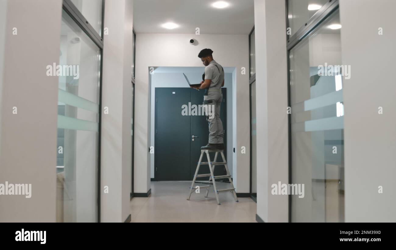 African american installer sets up security cameras in office room ...