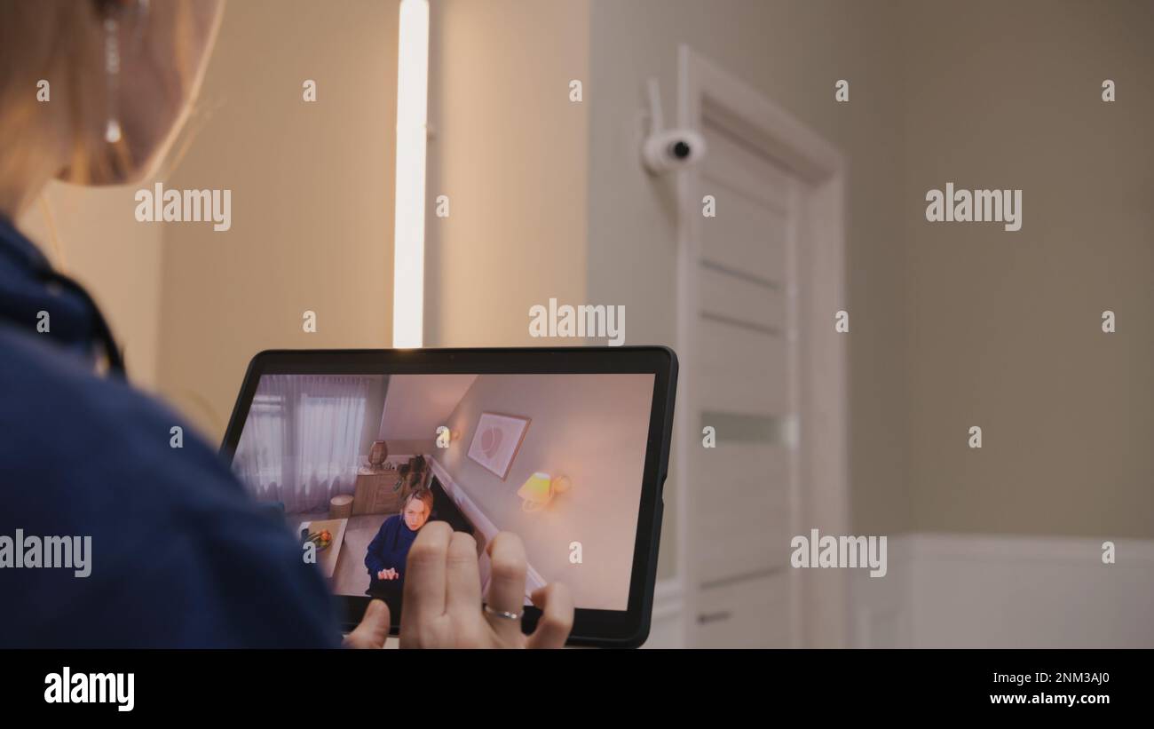 Caucasian woman checks security camera after installation. Woman sets ...