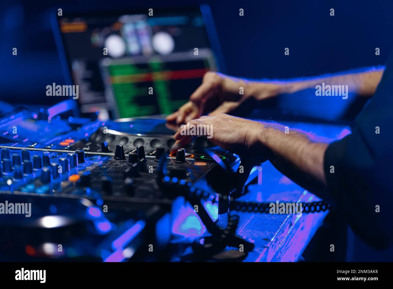 Hands of DJ playing music on rave party in night club. Professional ...