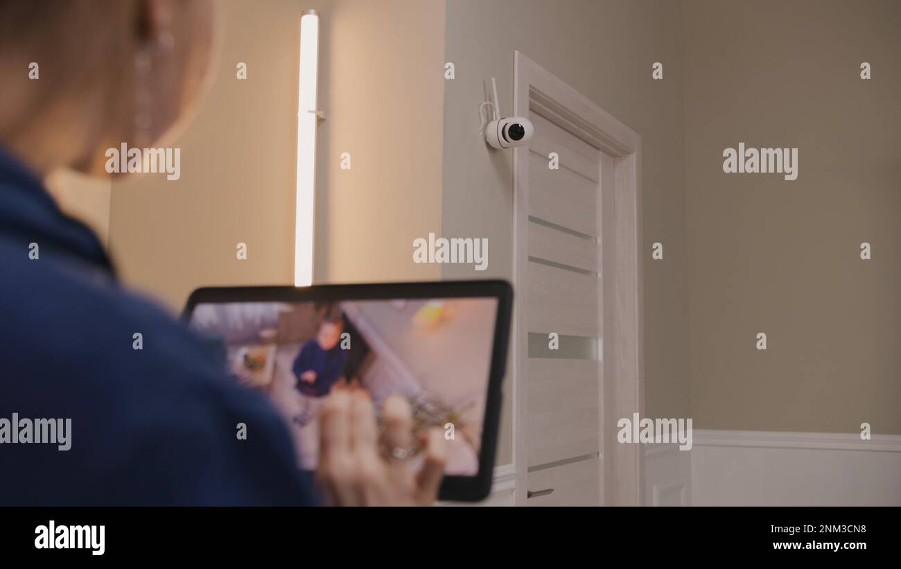Caucasian woman checks security camera after installation. Woman sets ...