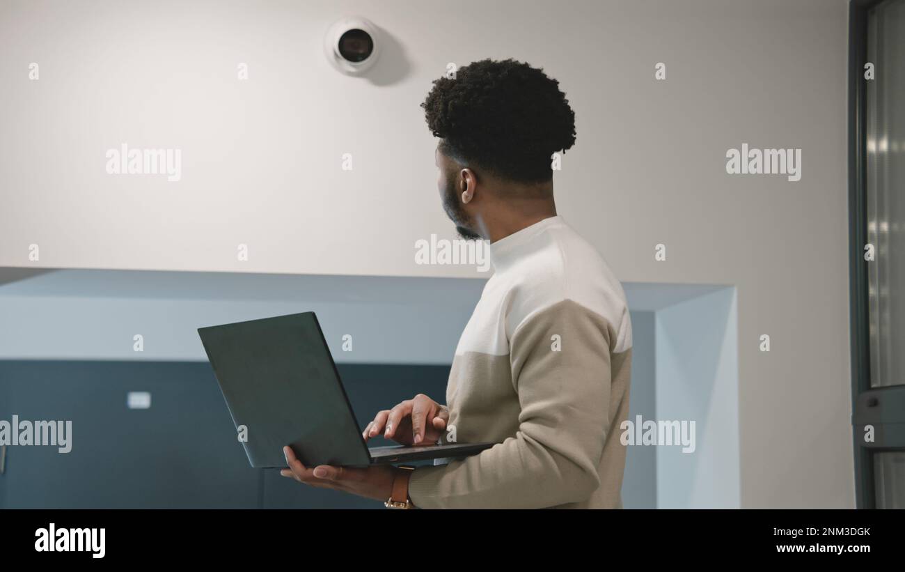 African american installer sets up security camera in office room using ...