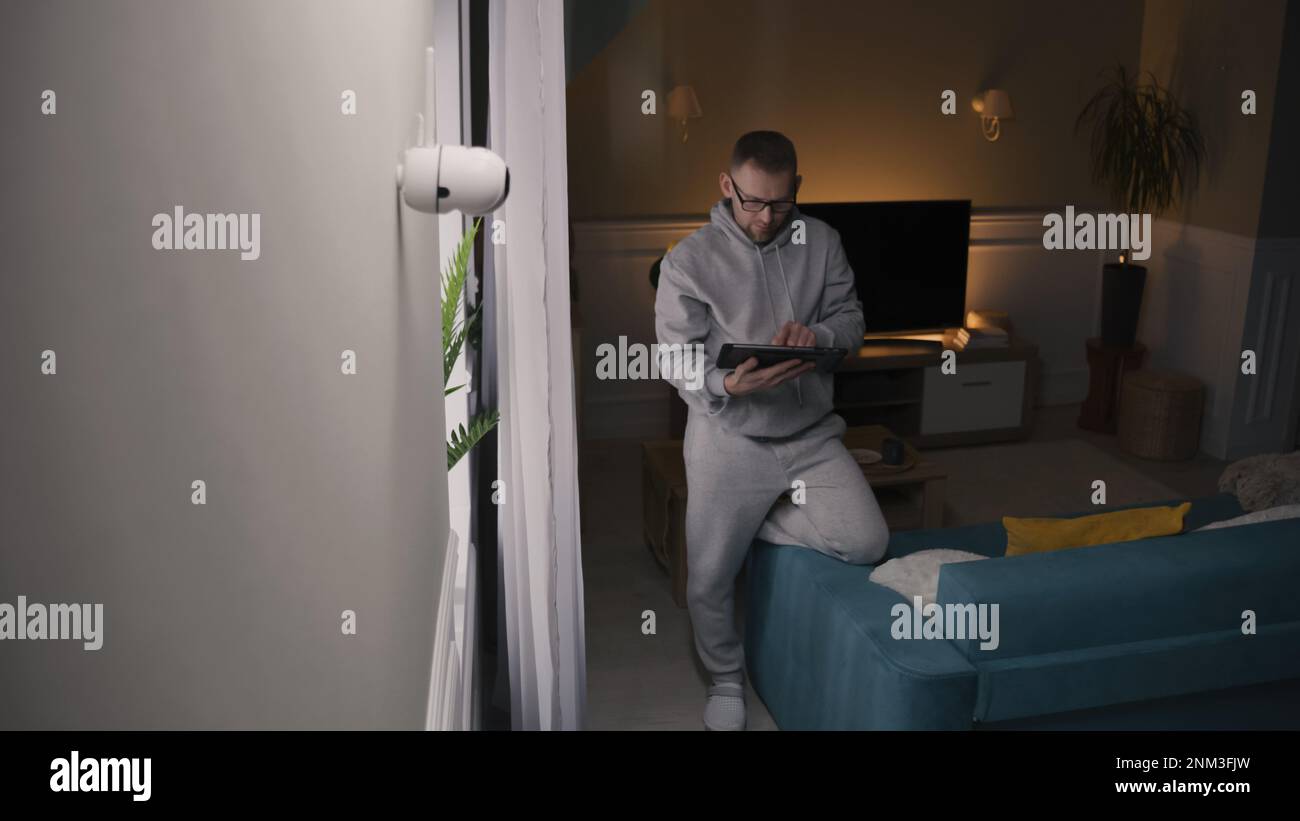 Caucasian man sets up security camera at home for the night. He turns ...